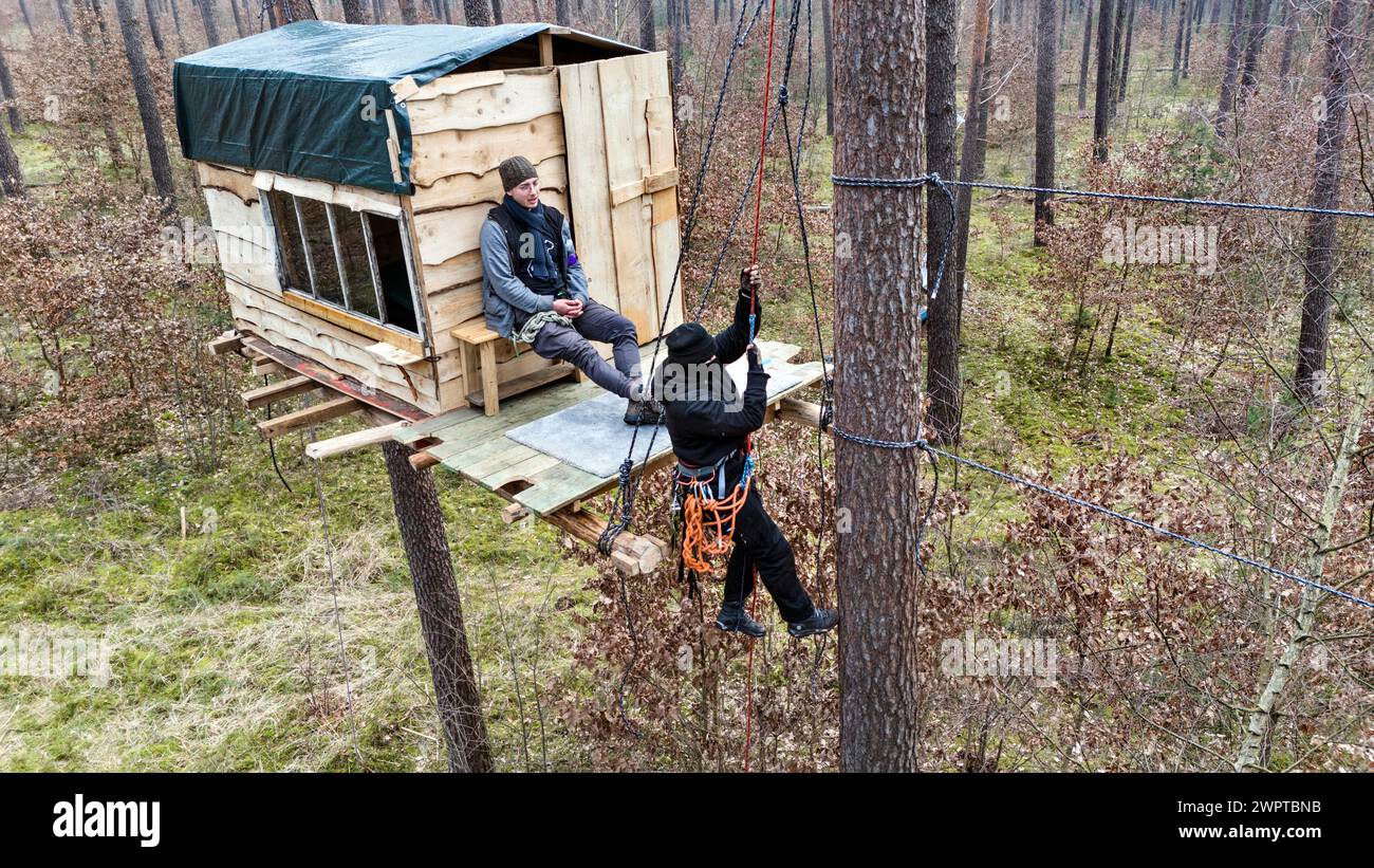 A climate activist pulls herself up a rope to a tree house in the ...