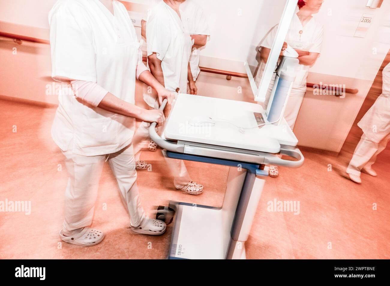 Nurses and care staff walk down a corridor in a hospital in Berlin with ...