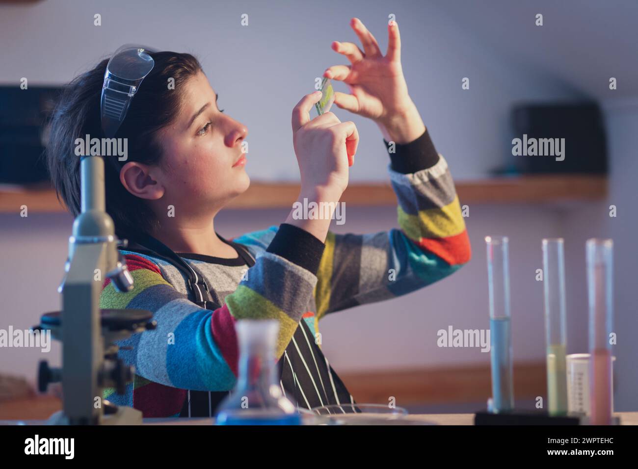 Cute young botanist in a home research laboratory wearing safety ...