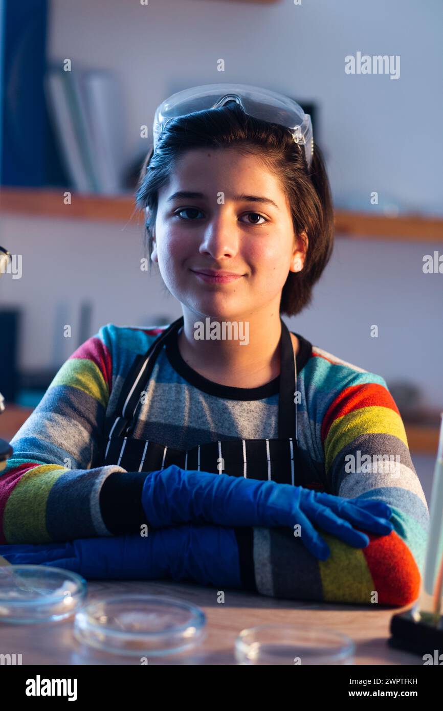 A wonderful Caucasian boy sits at a table in a home research laboratory ...