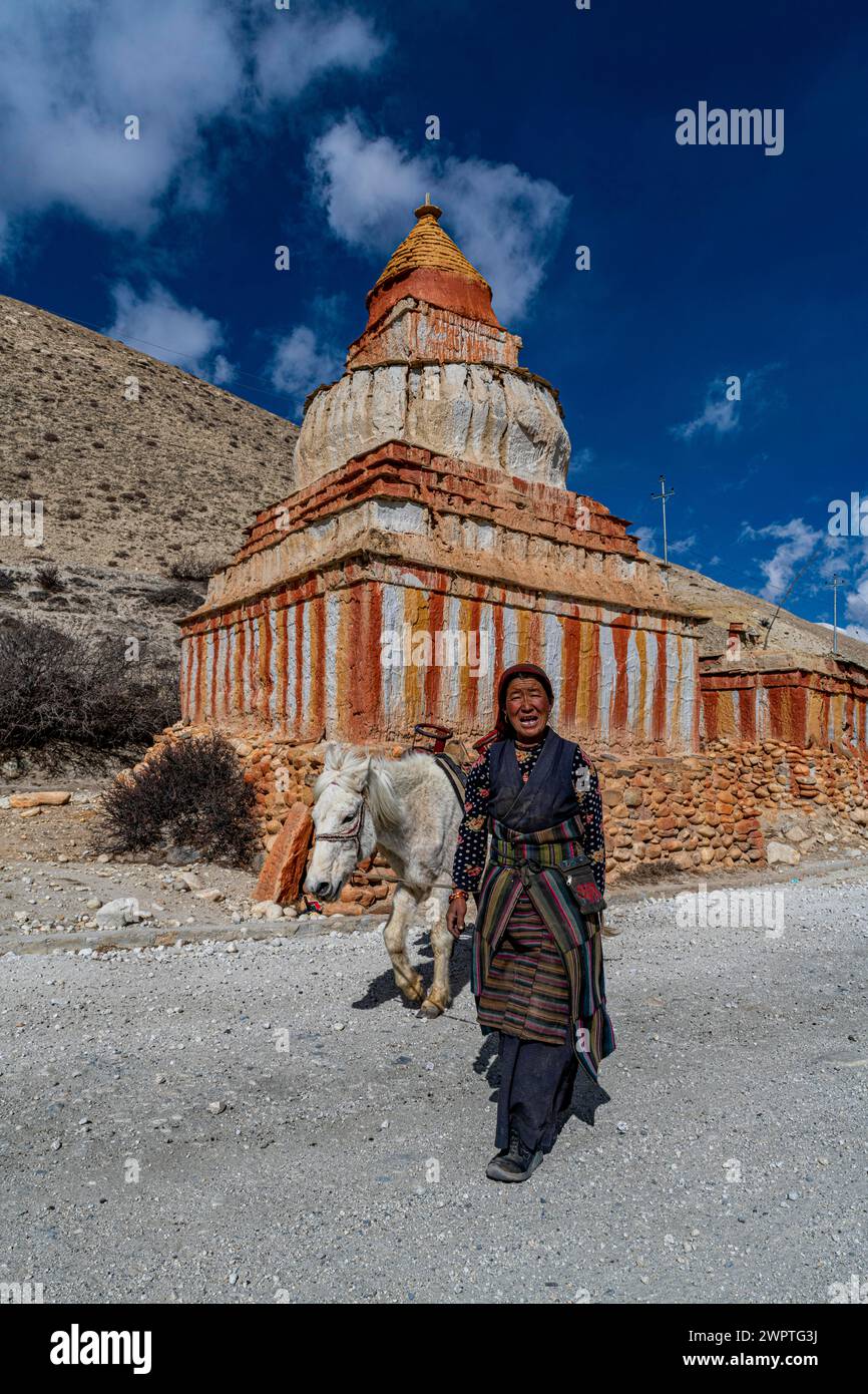 Woman with her horse, colourfully painted Buddhist stupa in front of ...