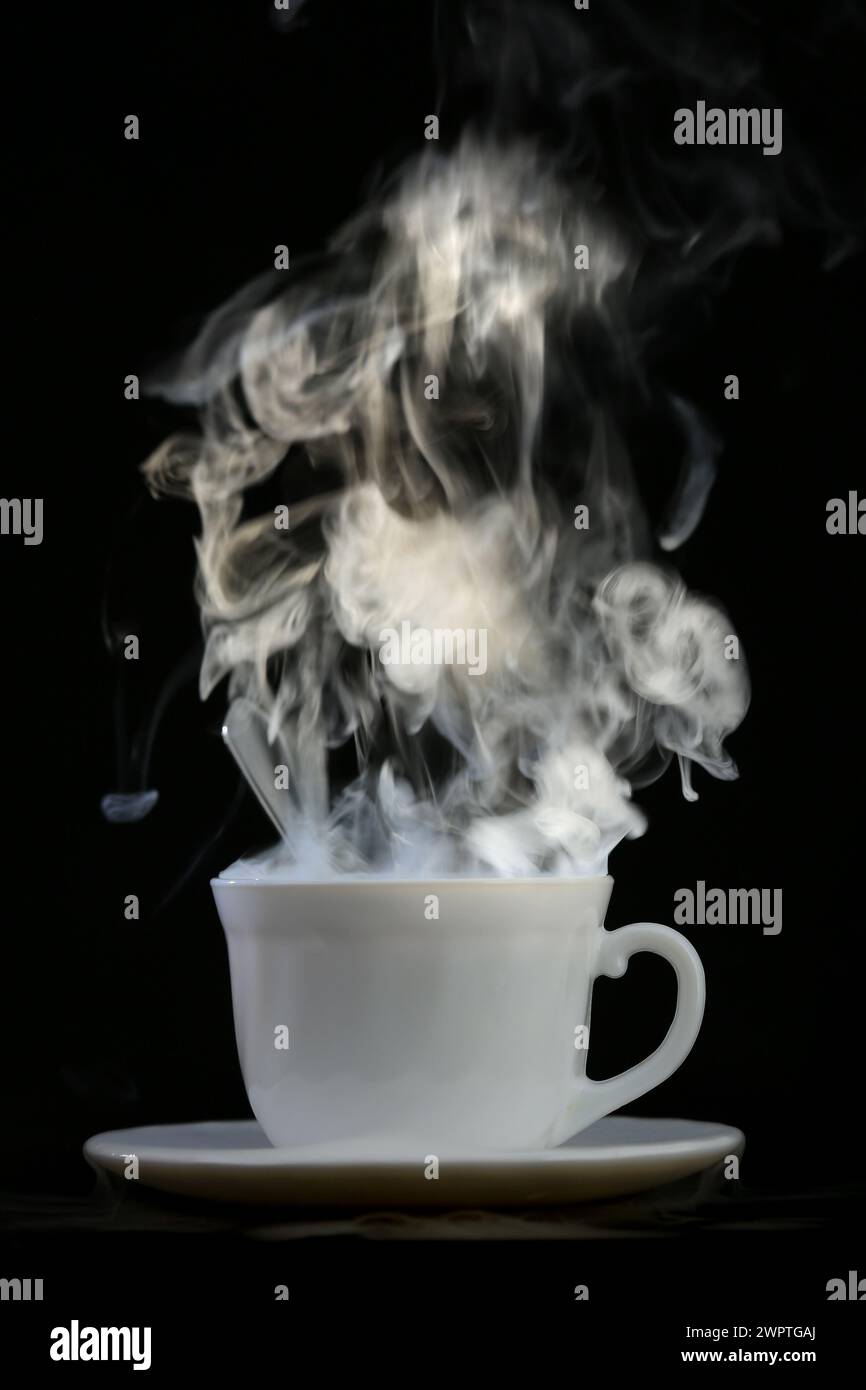 white cup with hot liquid and steam on black Stock Photo - Alamy