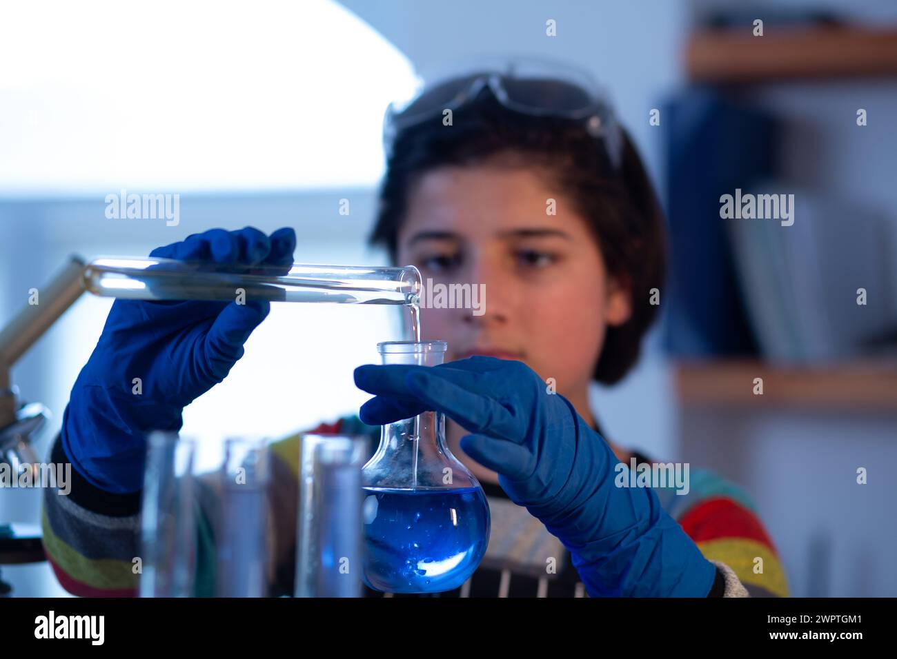 A cool teenager in a home research laboratory wearing safety glasses ...