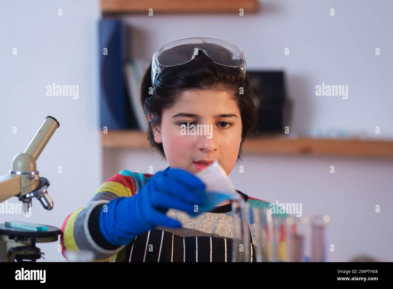 A Cool Young Nerd In A Home Research Laboratory Wearing Safety Glasses And Rubber Gloves Is