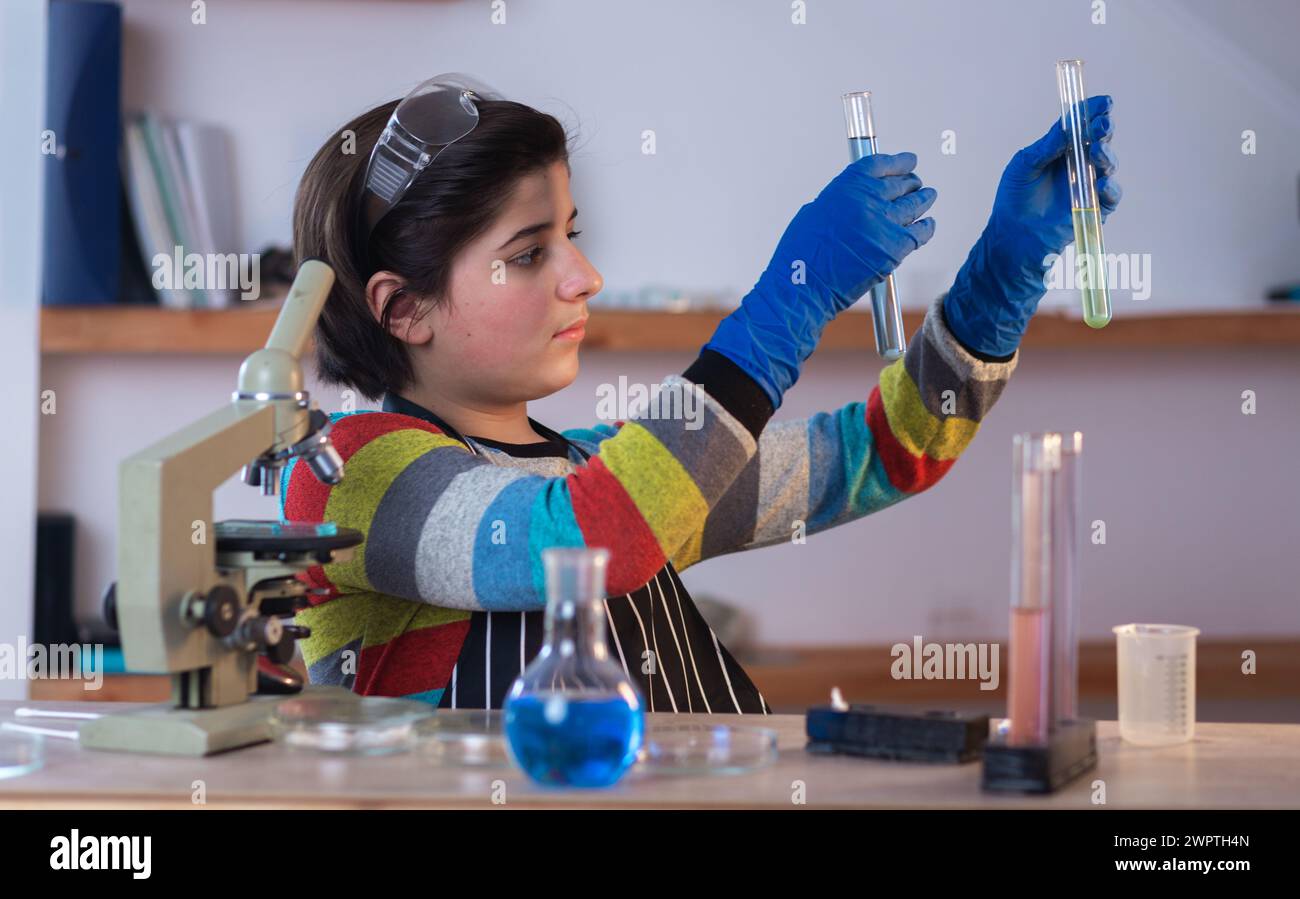 Advanced school science project. A cute Young Nerd in a home research laboratory wearing safety ...