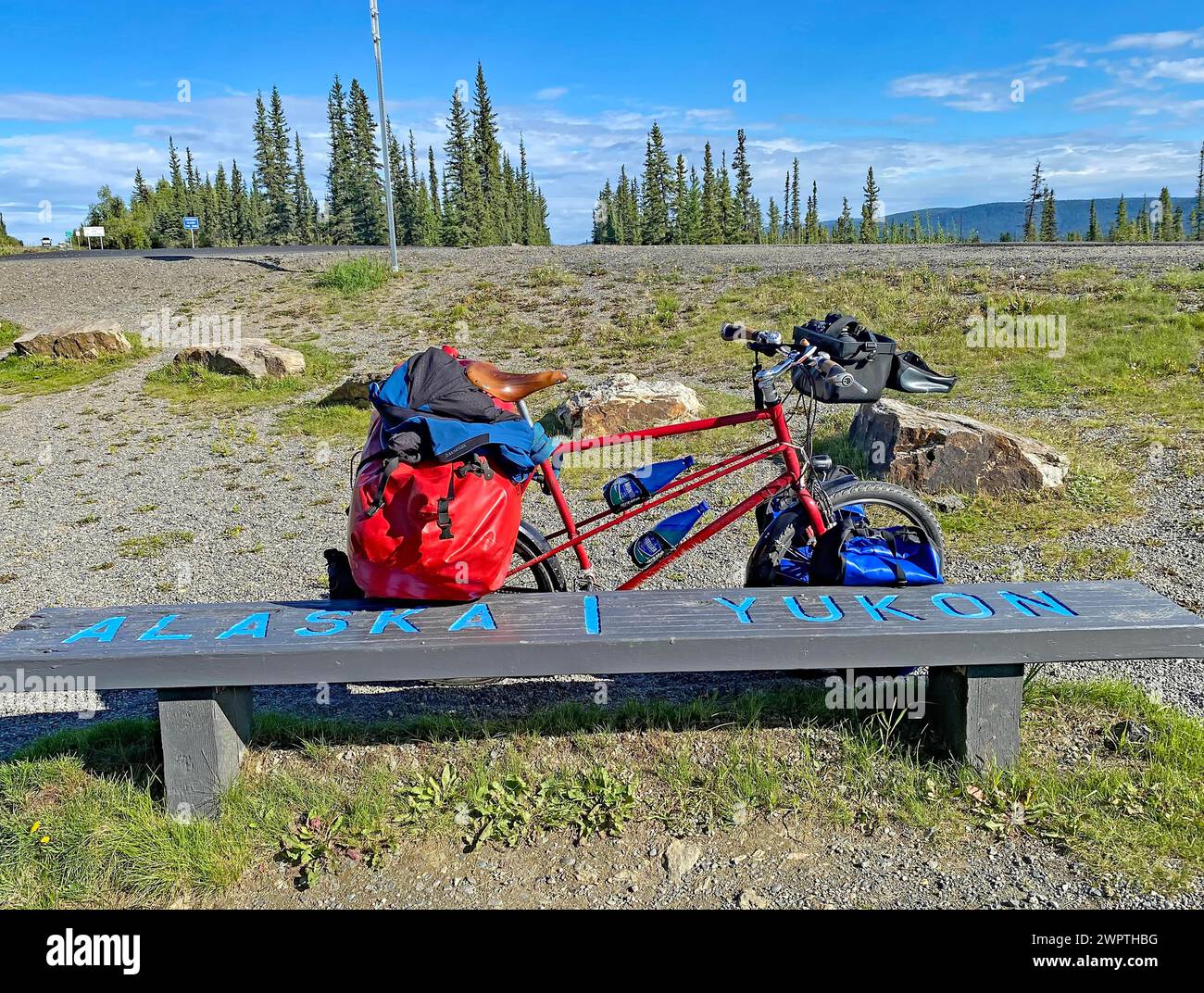 Bench right on the border between Alaska and the Yukon, packed touring bike, adventure ...