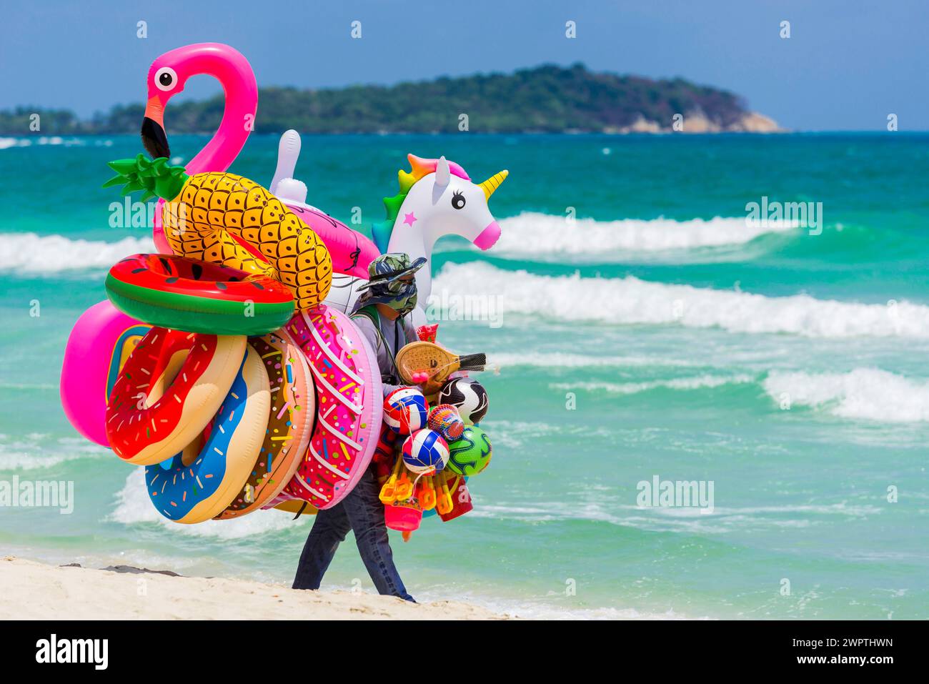 Merchant on the beach selling inflatable swimming aids, colourful ...