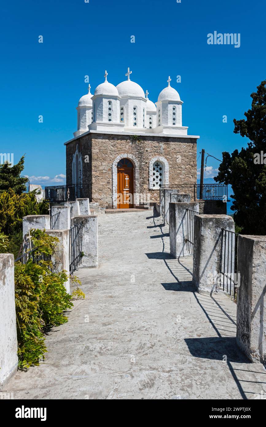 A white path leads to a church with blue domes under a bright blue sky ...
