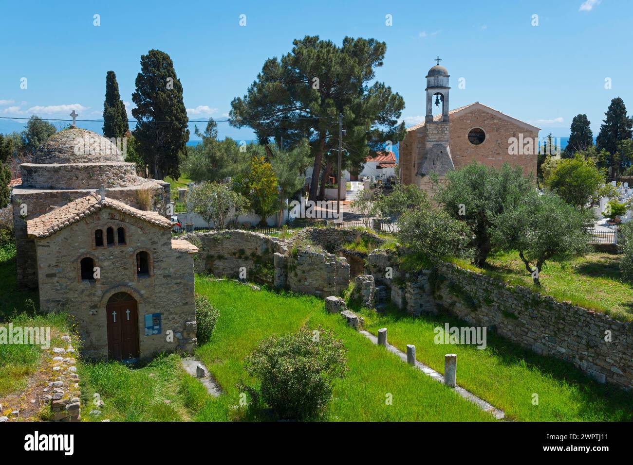 Old church surrounded by ruins in a rural area with tall cypress trees ...