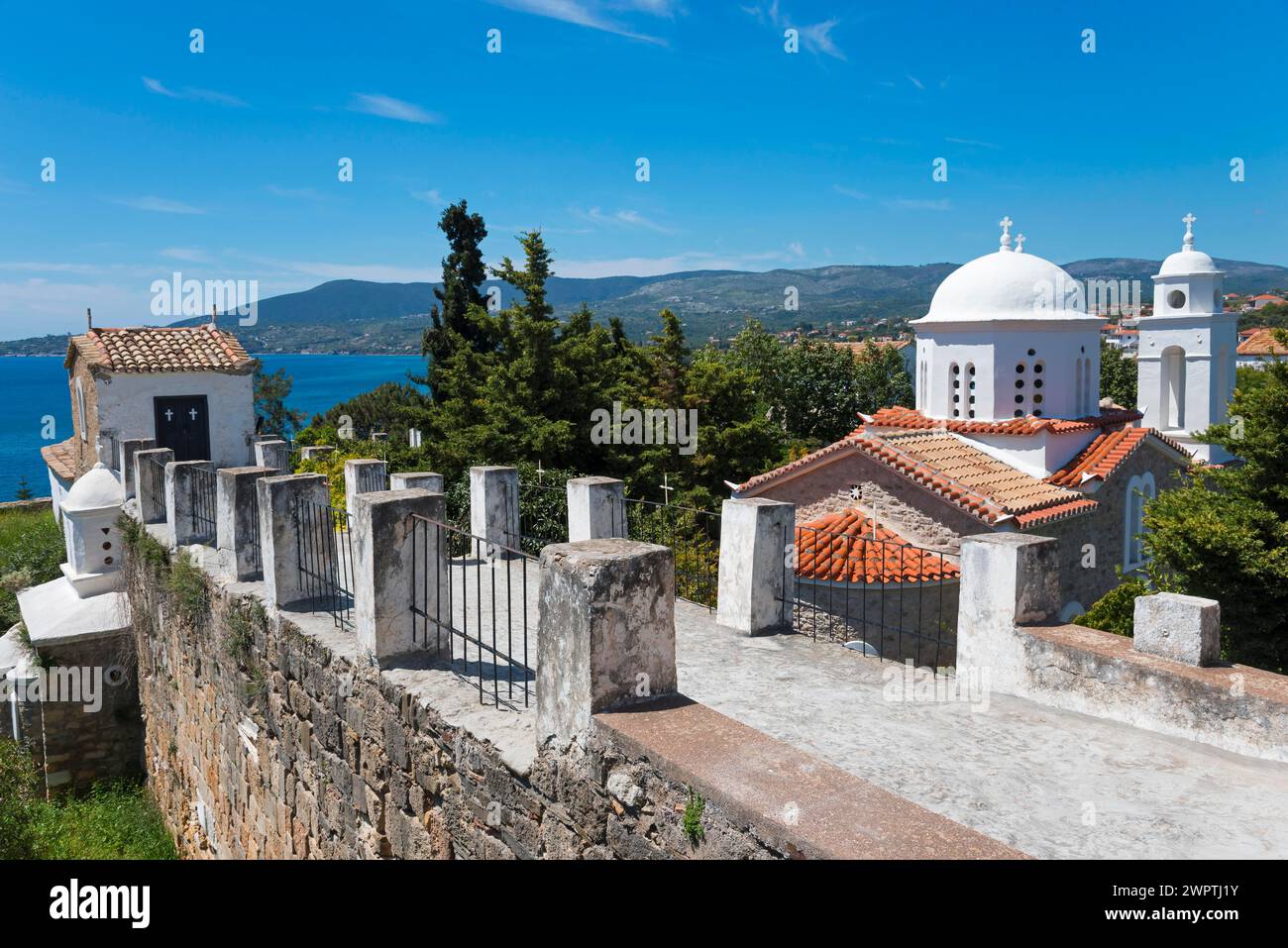 View of churches and the sea, surrounded by a stone wall and red roofs ...