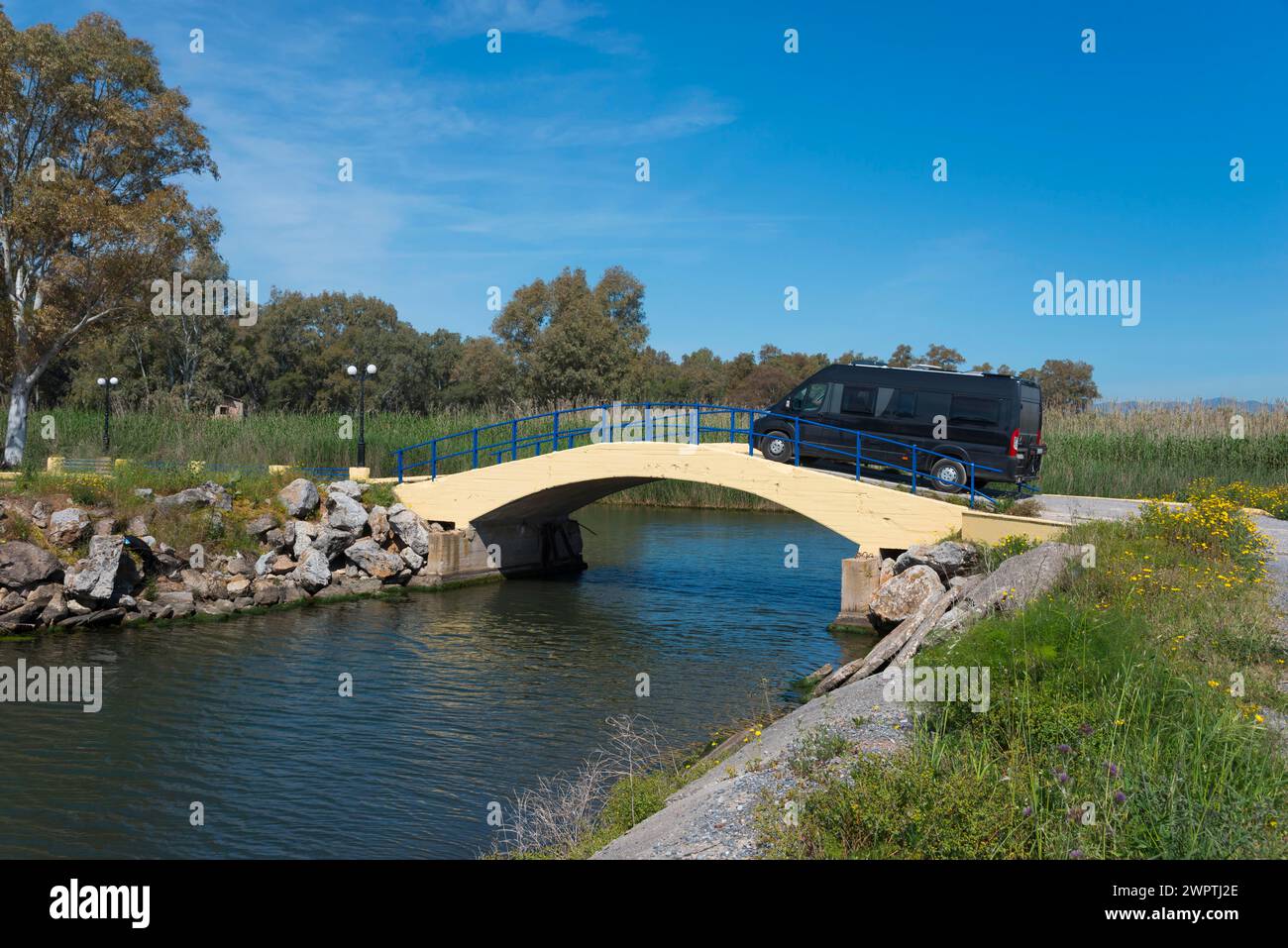 A motorhome drives over a small yellow bridge in a natural landscape on ...