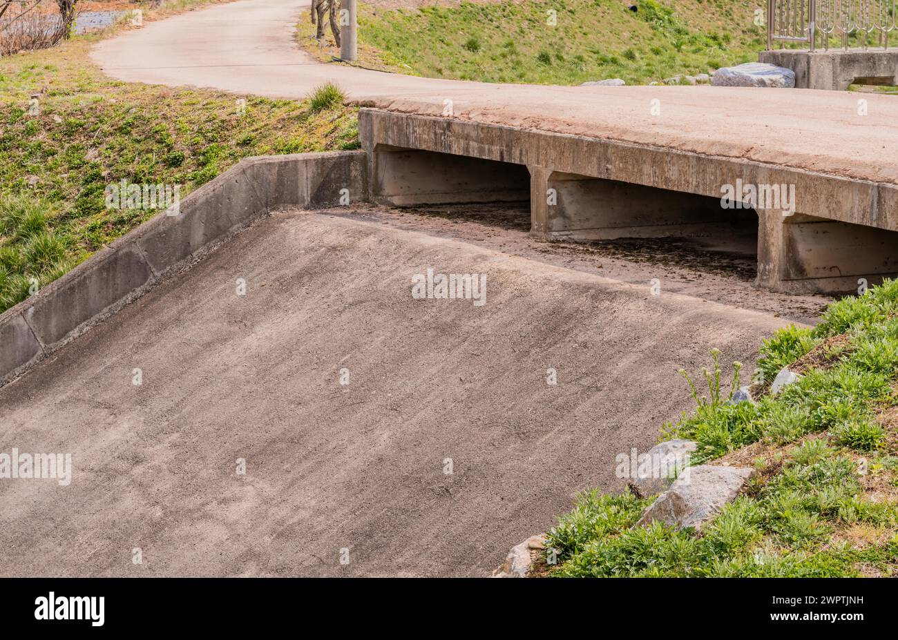 A basic concrete culvert under a pathway in a rural setting with an ...
