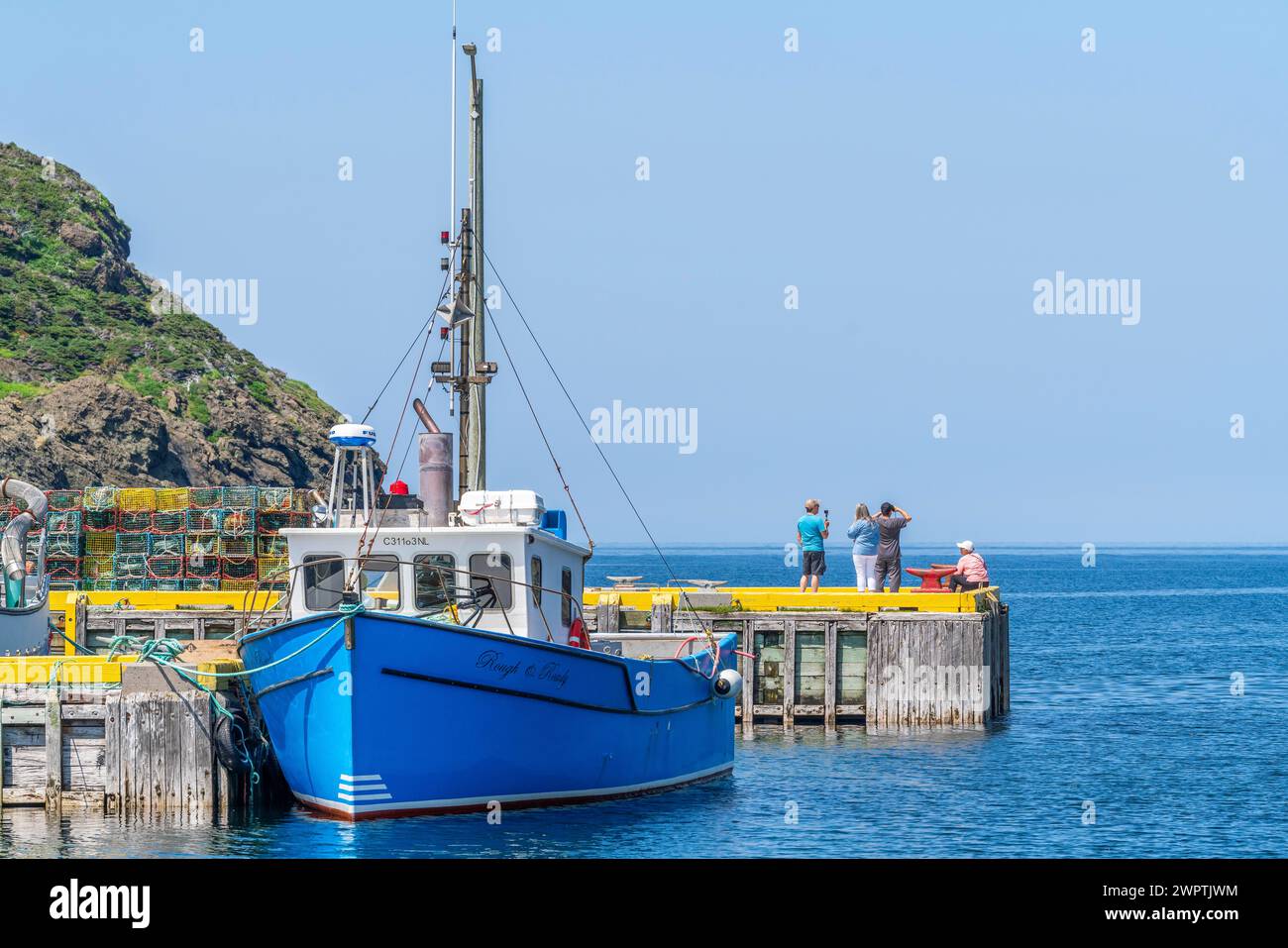 Blue fishing boat and tourists in the harbour of the fishing village ...