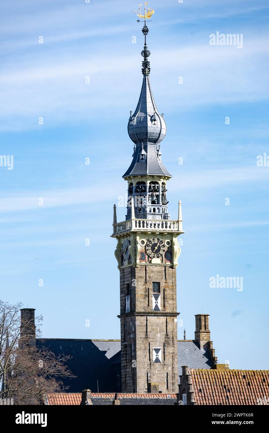 Old tower with a clock and spire rising above lower buildings ...