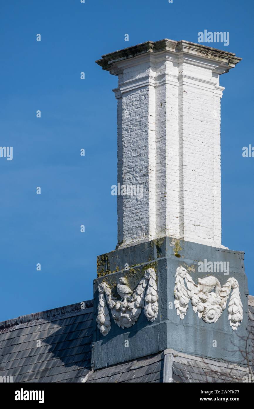 Close-up of a white chimney with decorative elements on a grey roof ...