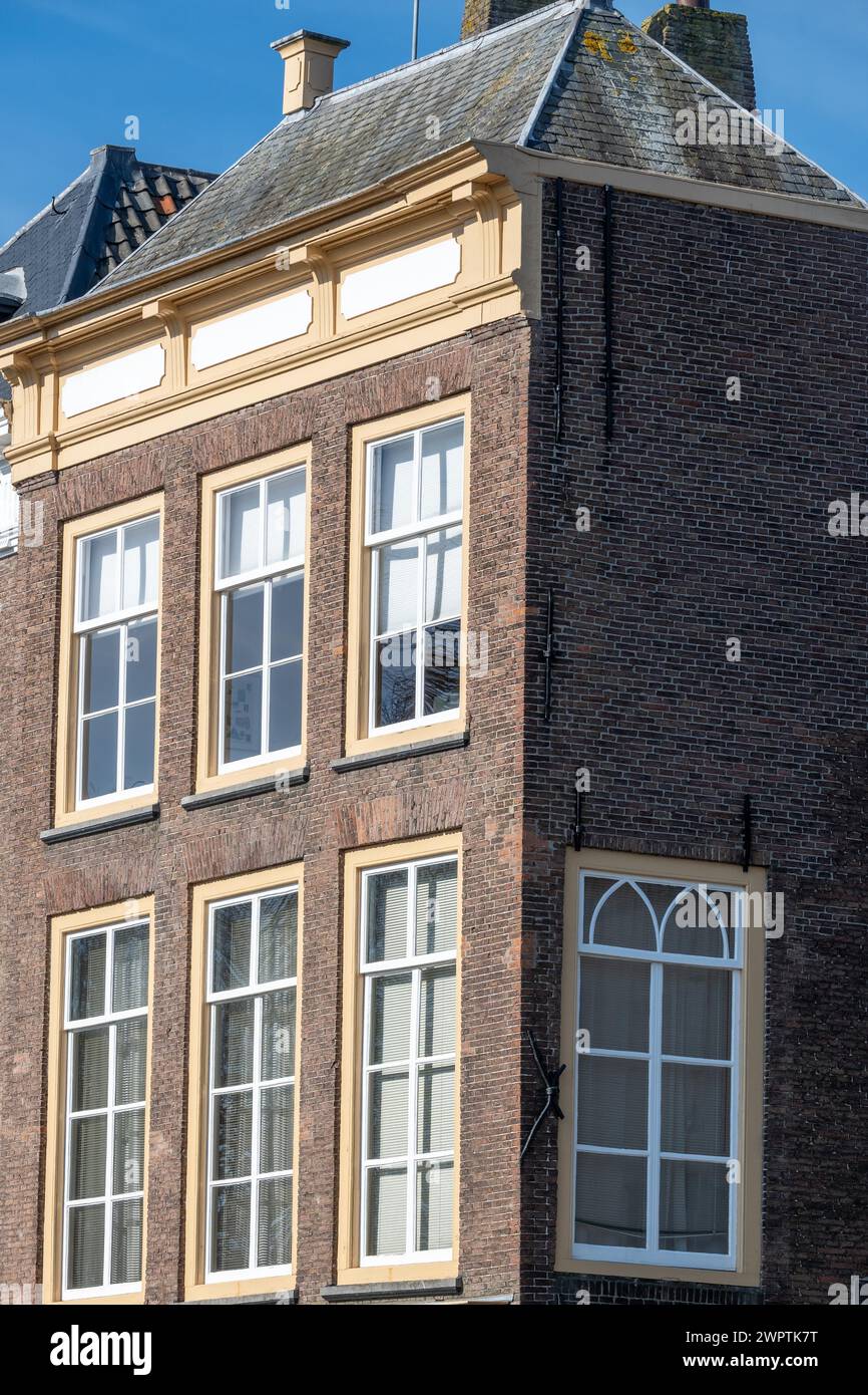 Side view of an old brick building with gabled roof and several windows ...