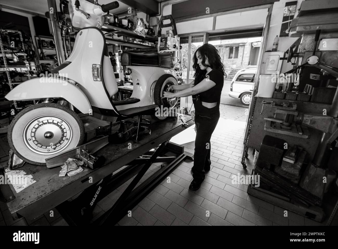 Woman mechanic working on repairing a white moped italian vintage ...