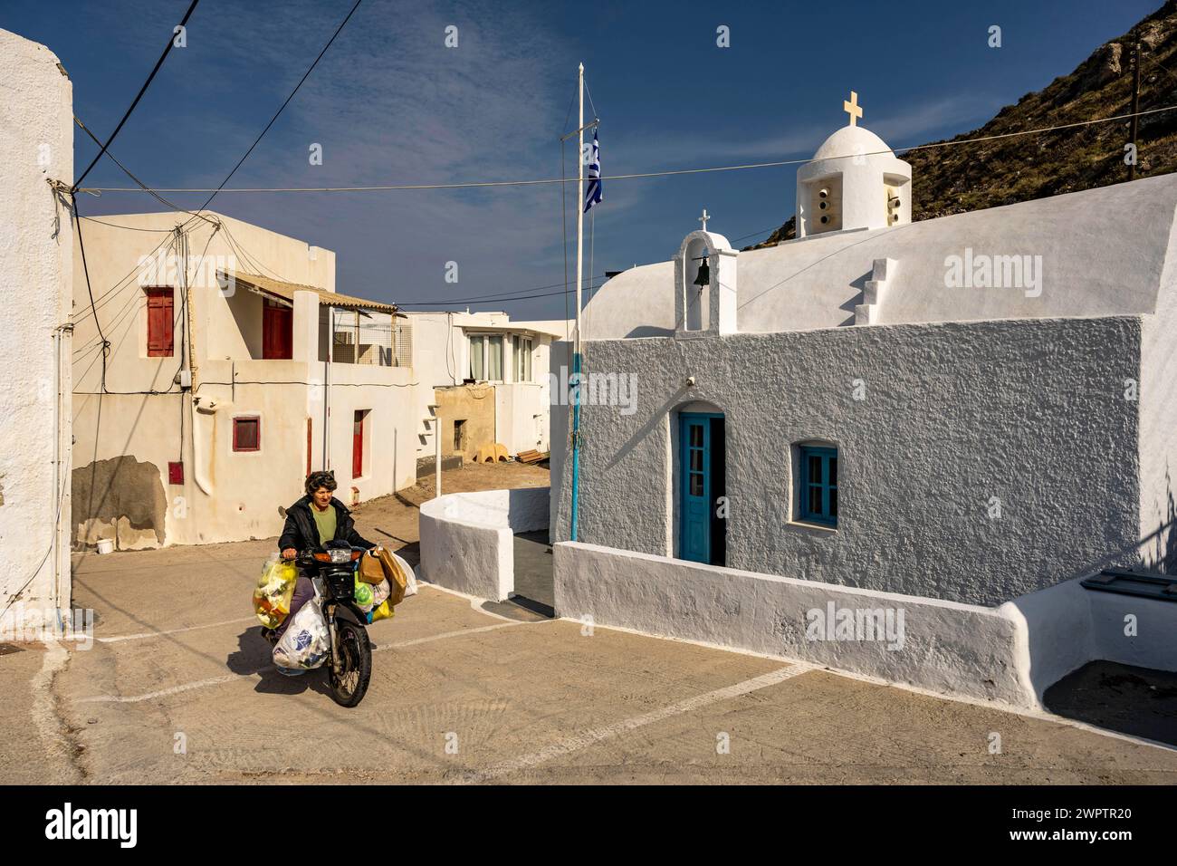 Woman riding a heavily loaded moped in front of Agios Dimitrios Church ...
