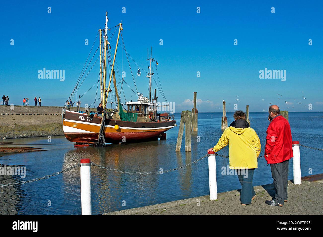 Fishing boat, Neuharlingersiel, marvelled at by 2 tourists, dry dock ...