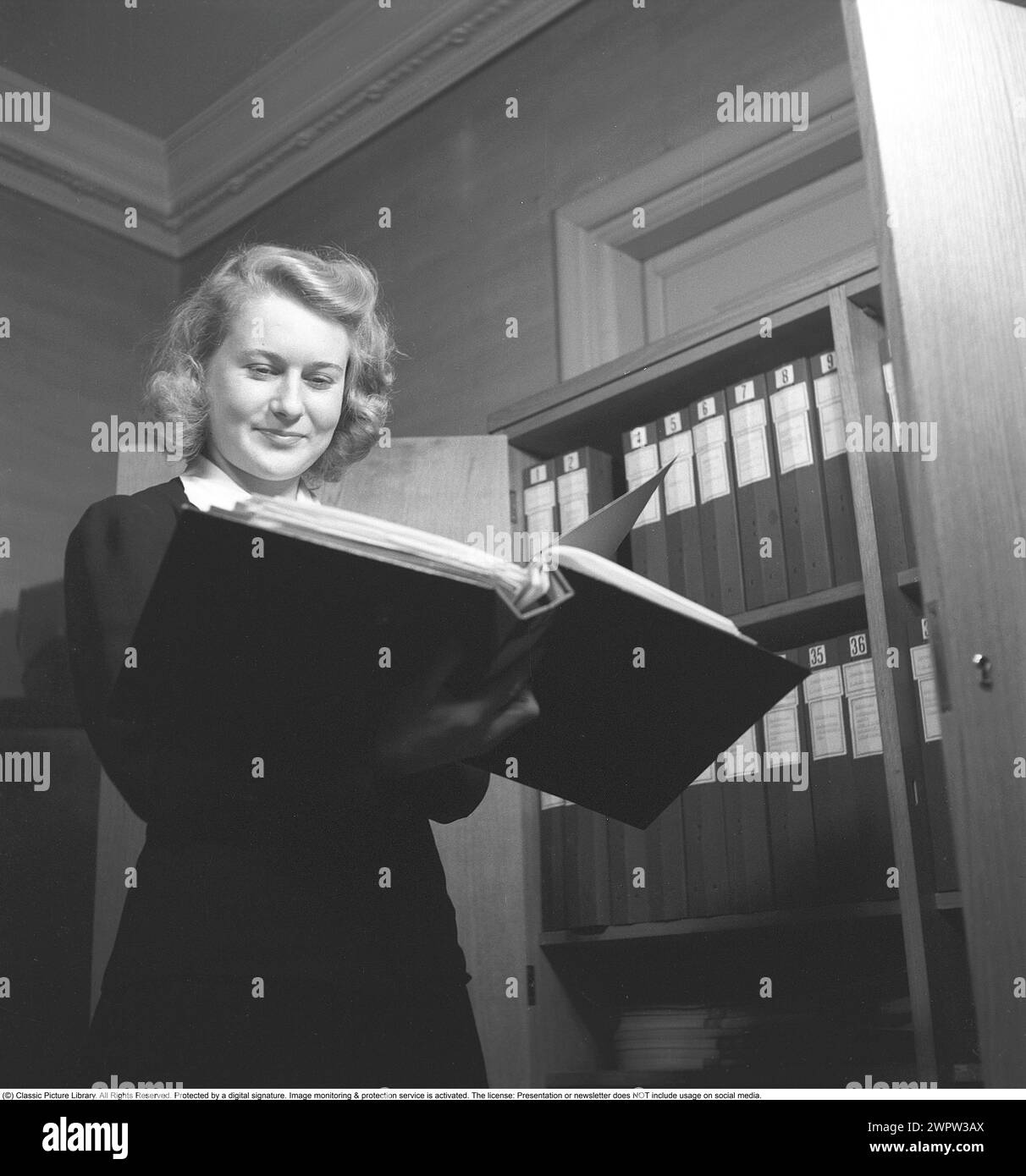 Woman in an office in 1942. A young female employee flips through the ...