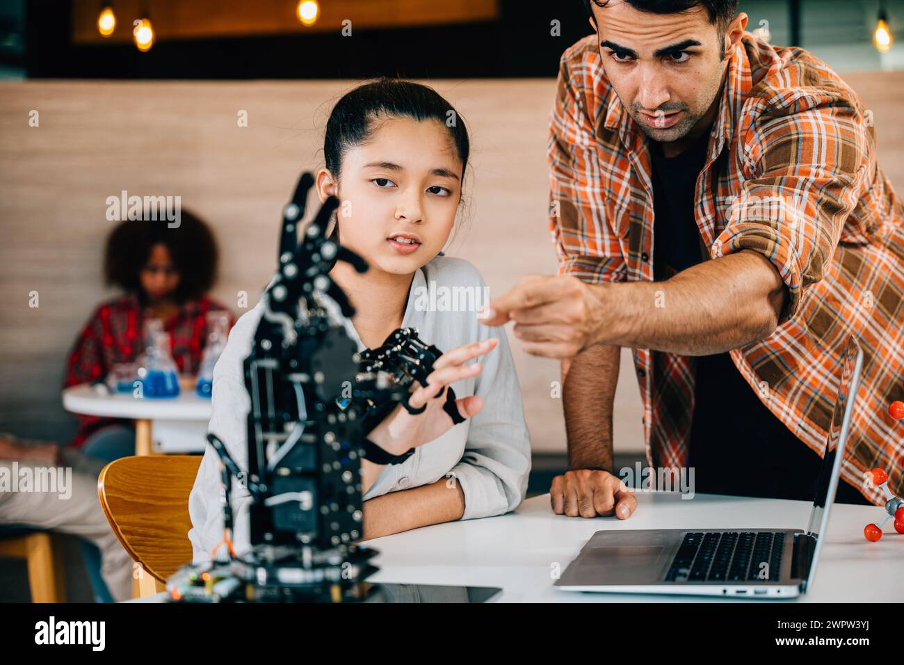 Teacher helps student construct a robotic arm in classroom design and ...