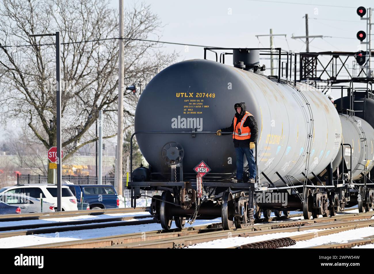 Franklin Park, Illinois, USA. A switchman fides the platform and holds the rail of a loaded tank ...
