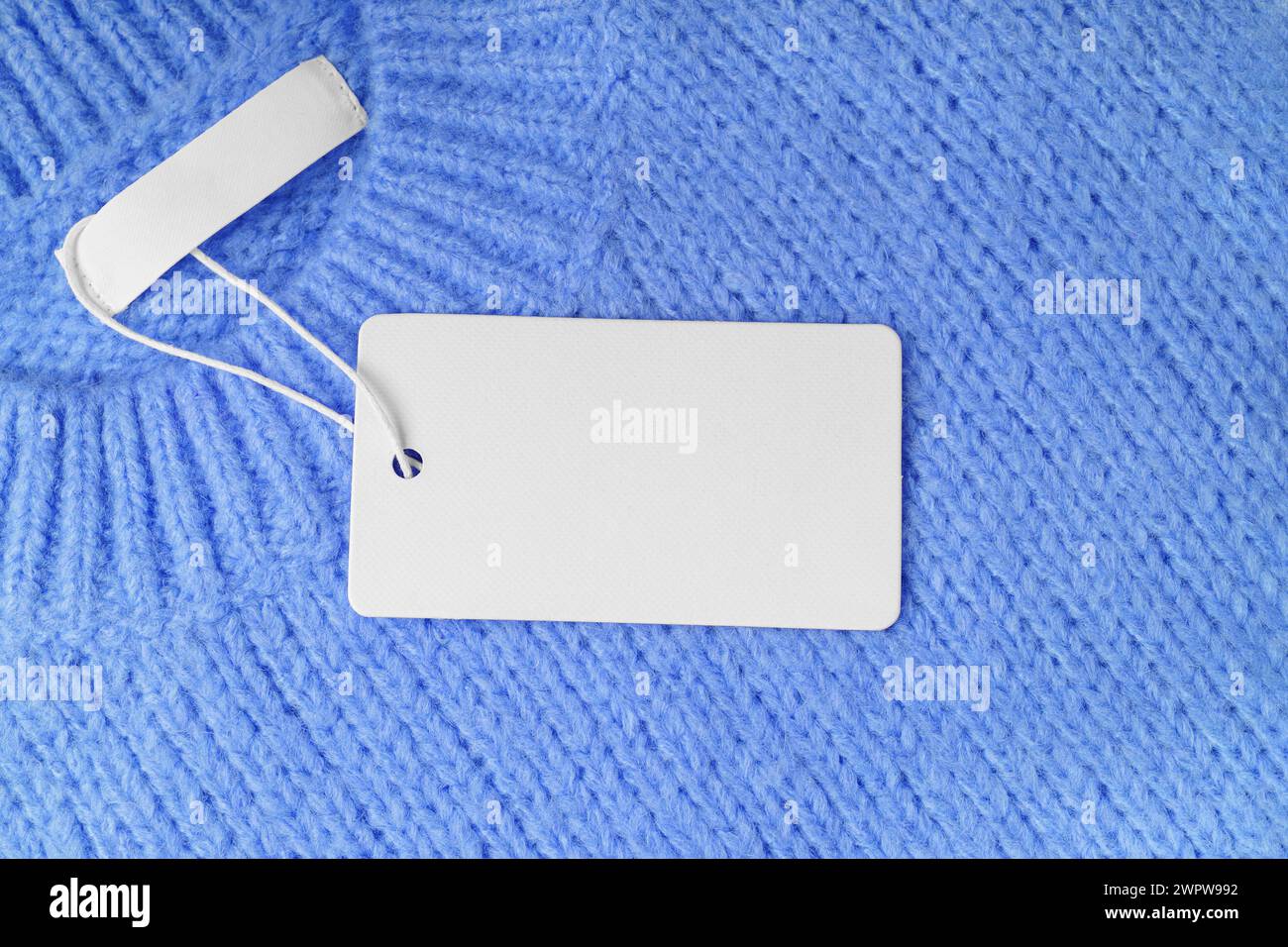 Blank clothing tag and inner label on neck of blue knitted sweater ...