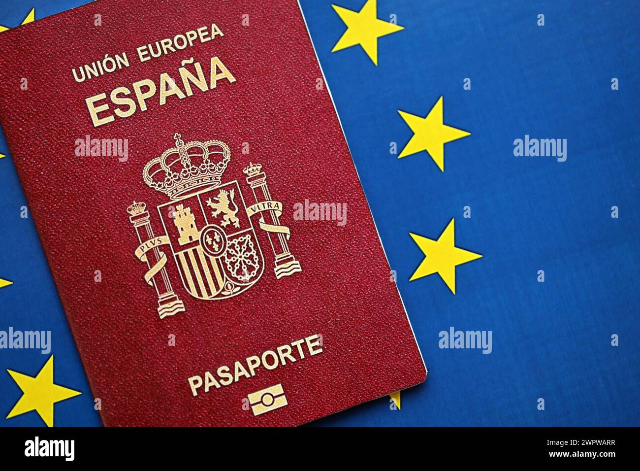 Red Spanish passport of European Union on blue flag background close up ...
