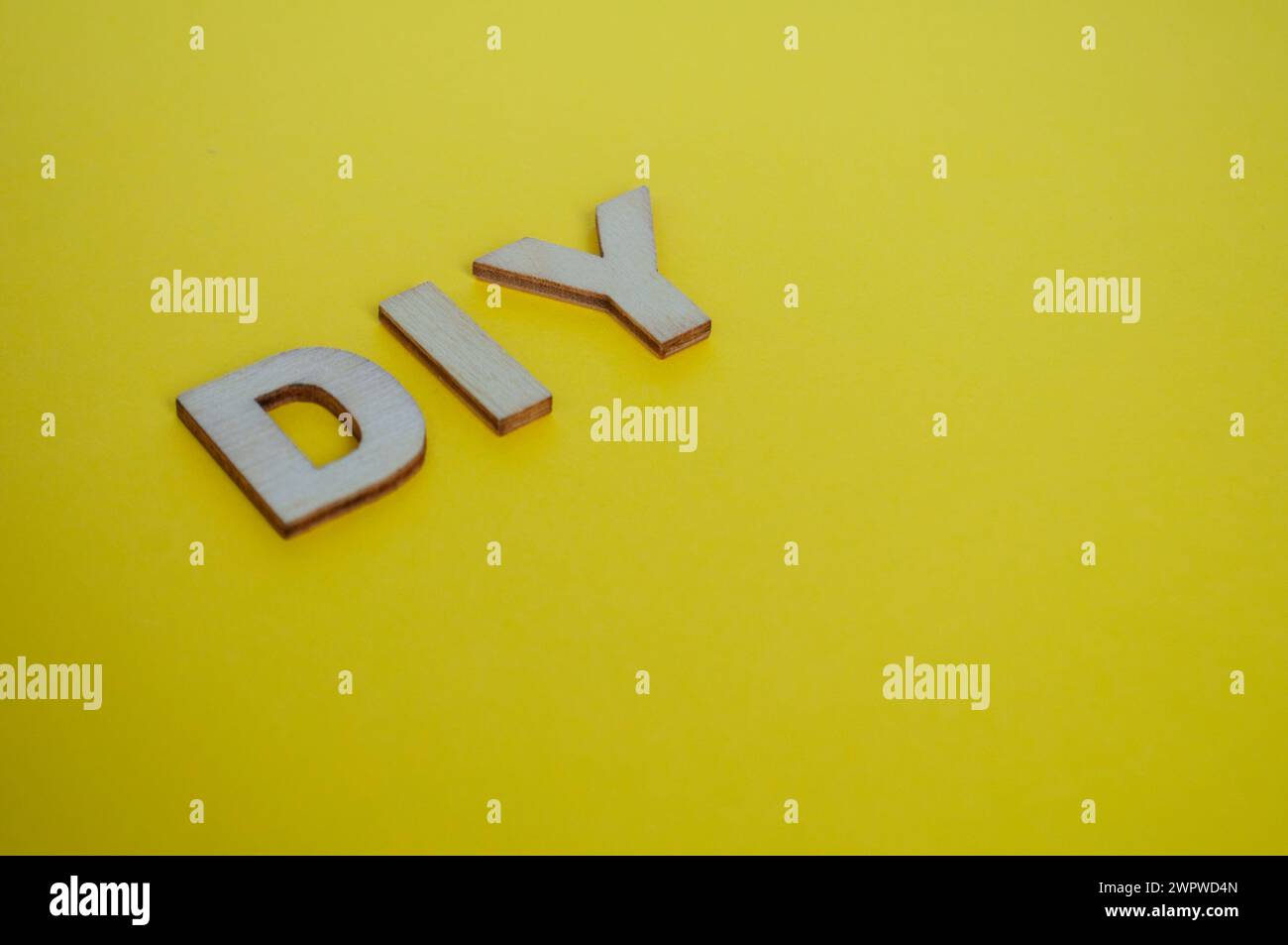 DIY wooden letters representing Do It Yourself on yellow background ...