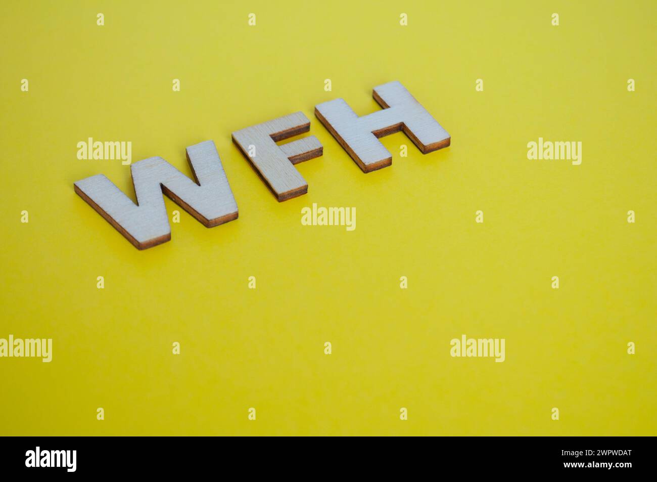 WFH wooden letters representing Work From Home on yellow background ...
