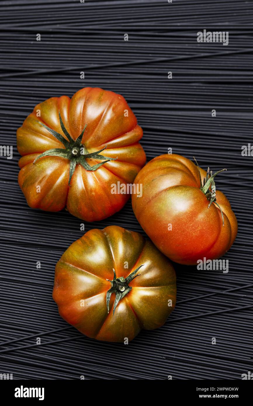 A trio of succulent ripe Raf tomatoes on a mound of black pasta Stock ...