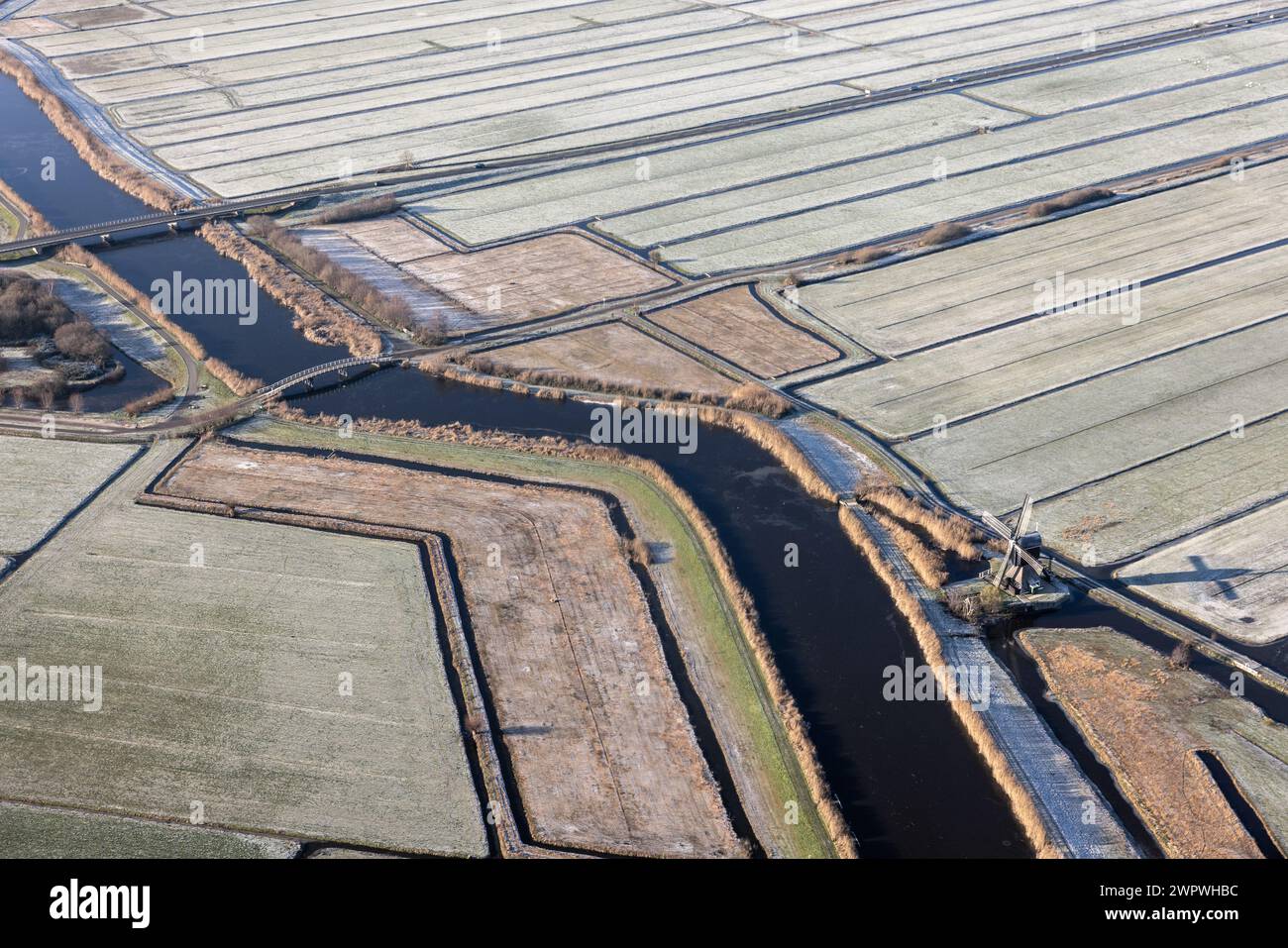Aerial view above dutch landscape with frozen meadows and ditches ...