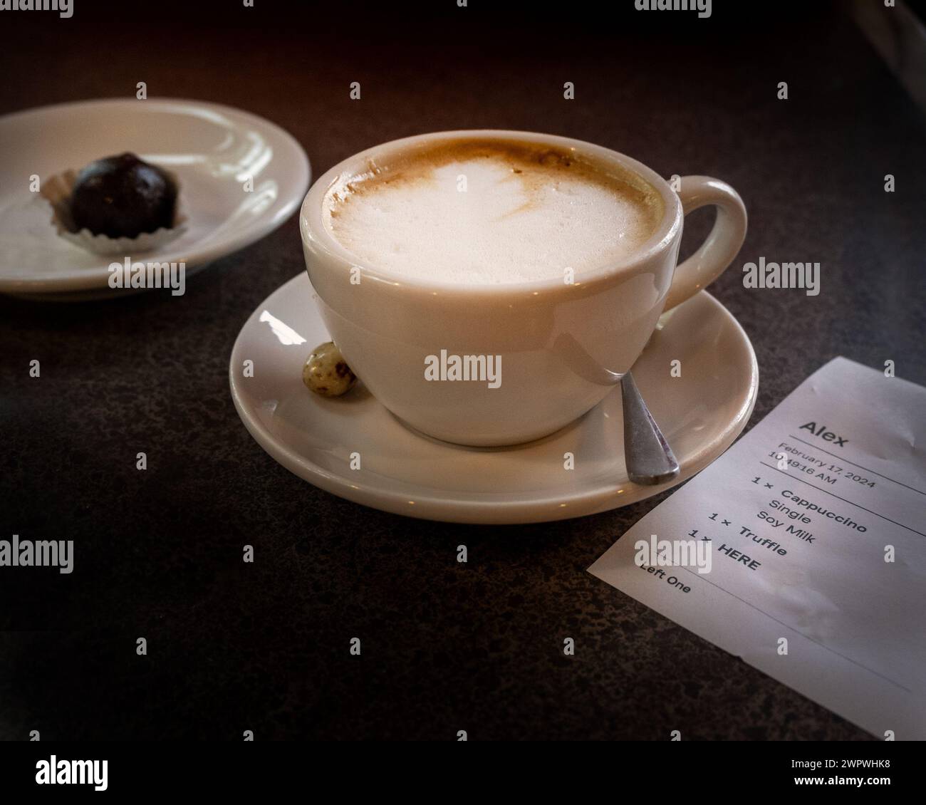 A cup of soy cappuccino and a chocolate truffe in a café showing the ...