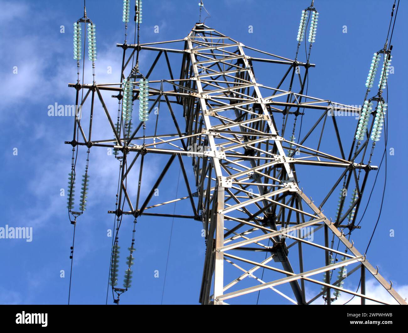 Top section of high-voltage power line metal prop over blue sky angled ...