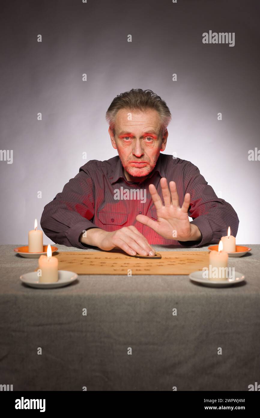 Older spiritist communicating with ghosts through ouija Stock Photo - Alamy