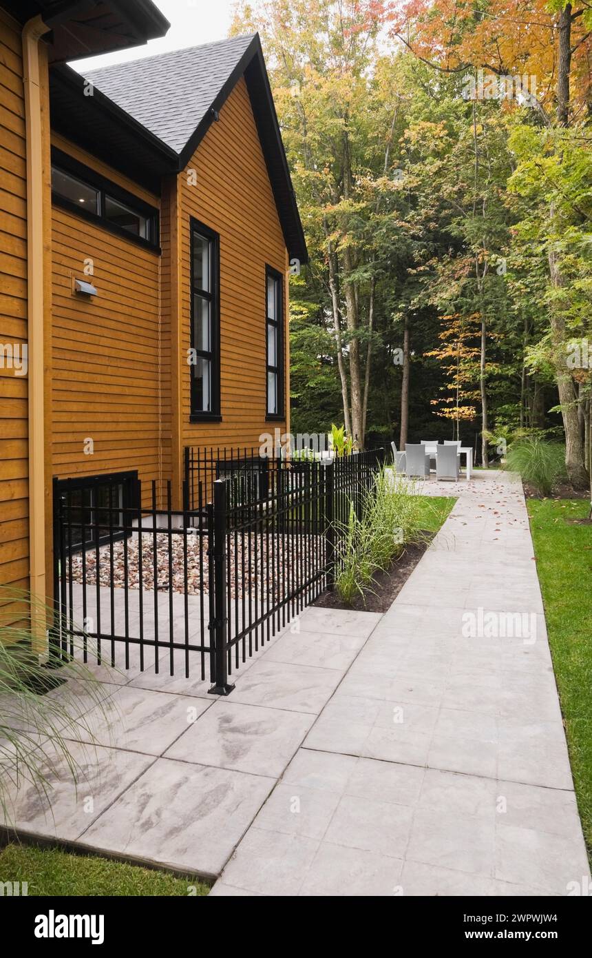 Paving tiles path leading to landscaped backyard of stained brown ...