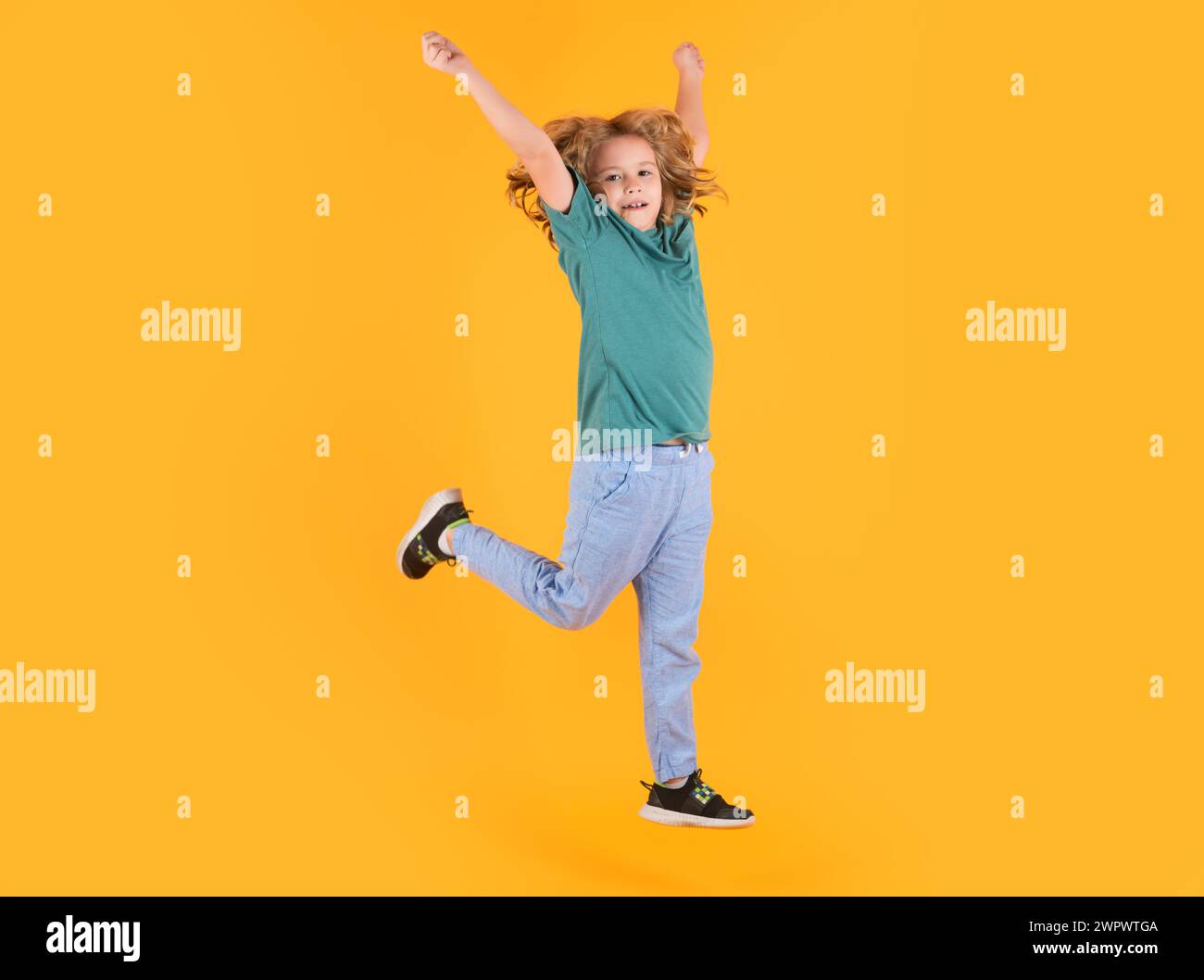 Energetic kid boy jumping and raising hands up on isolated studio ...