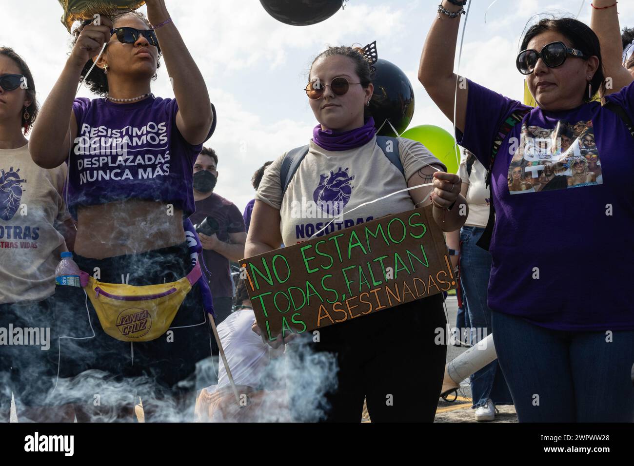 A feminist activist holds a sign reading “not all of us are here, we're ...
