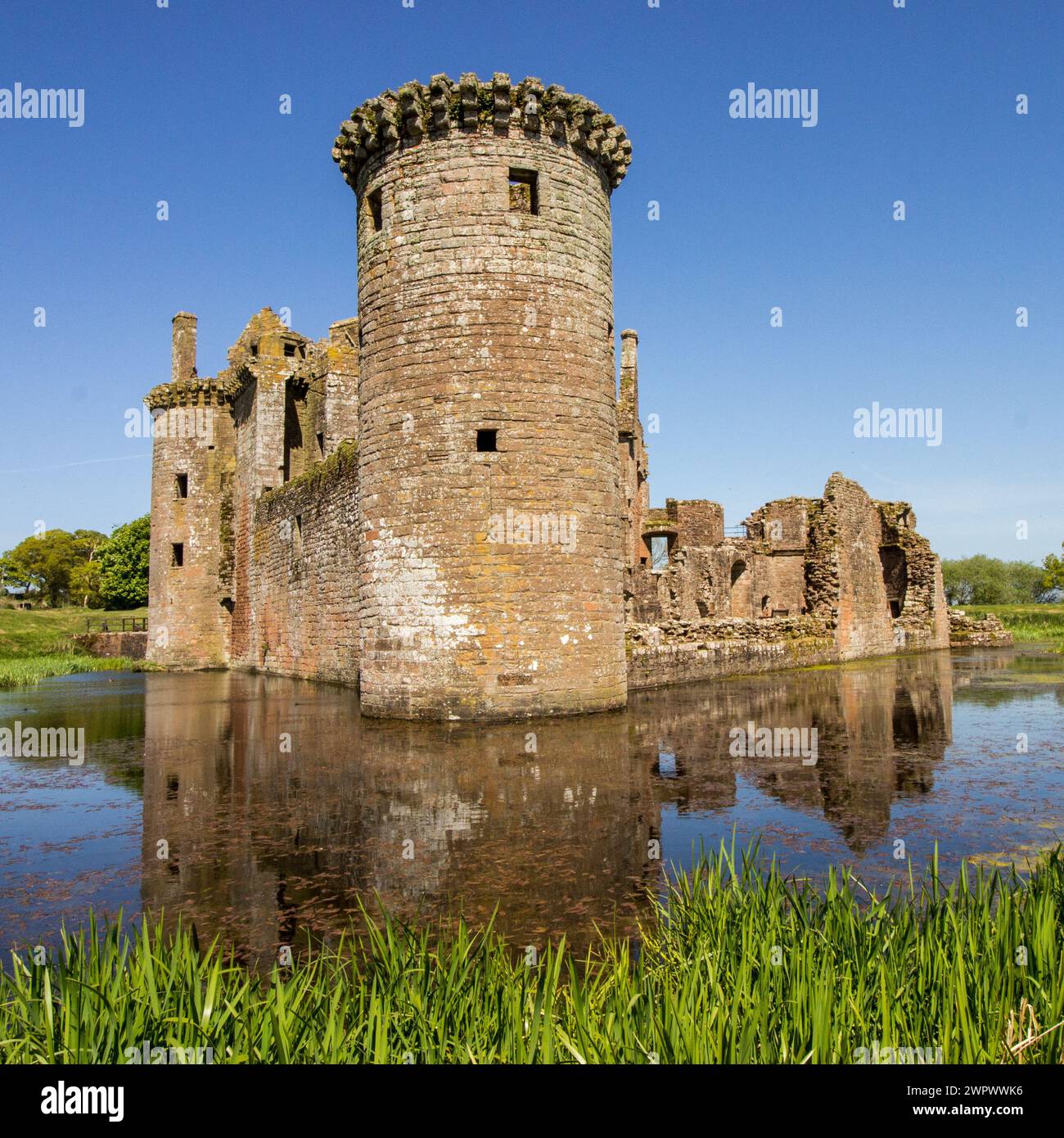 Castle ruins reflection in the surrounding moat on a clear sunny day in ...
