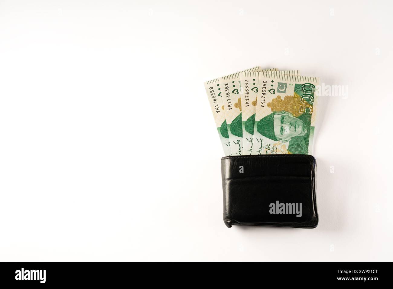 Five hundred rupee bank notes aligned with a black leather wallet ...