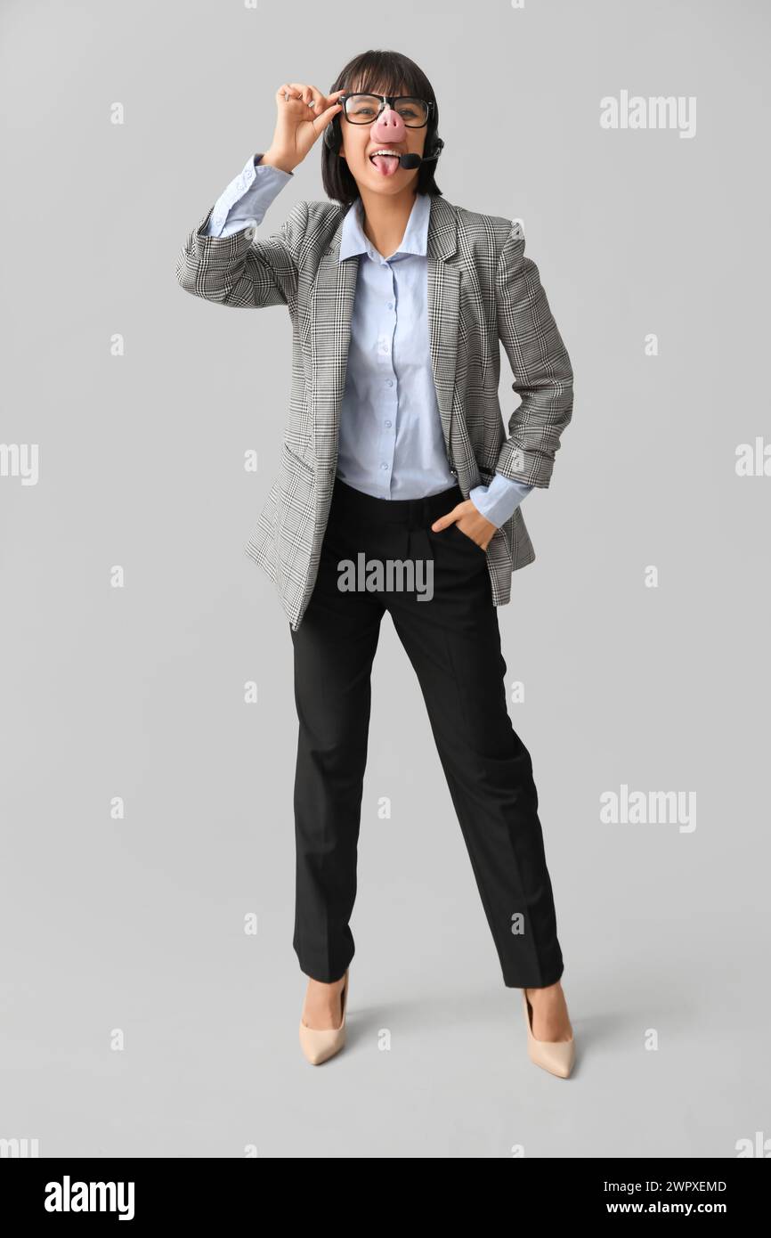 Funny young female technical support worker with headset and pig nose ...