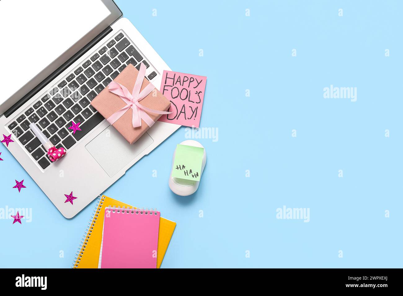 Laptop, gift box, notebooks and sticky notes on blue background. April ...