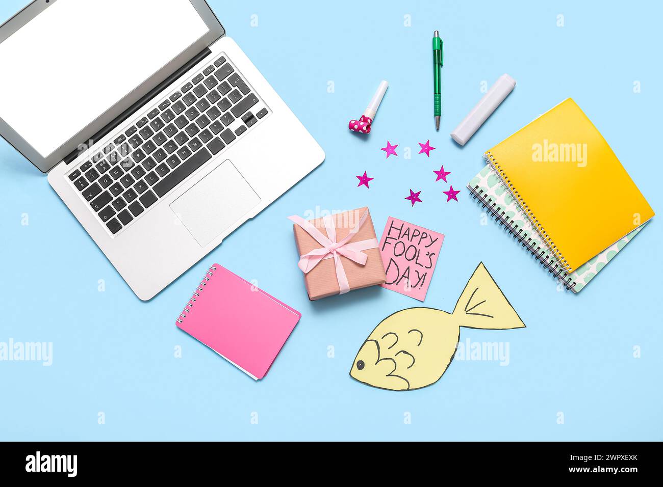 Laptop, gift box, notebooks and sticky notes on blue background. April ...