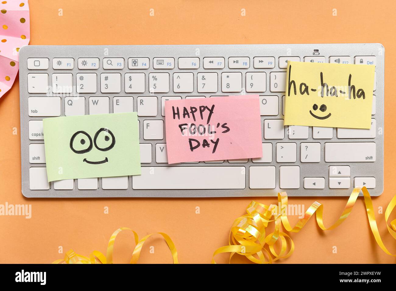 Computer keyboard and sticky notes on orange background. April Fools ...