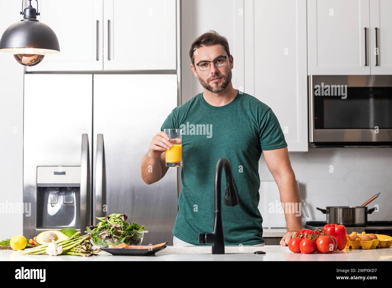 Handsome man cooking in kitchen. Mature man cooking with vegetables and ...