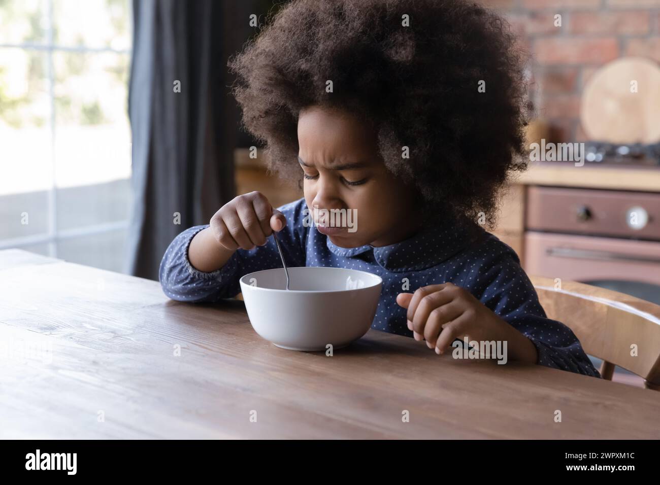 Little African girl frowning while eats not delicious breakfast Stock ...