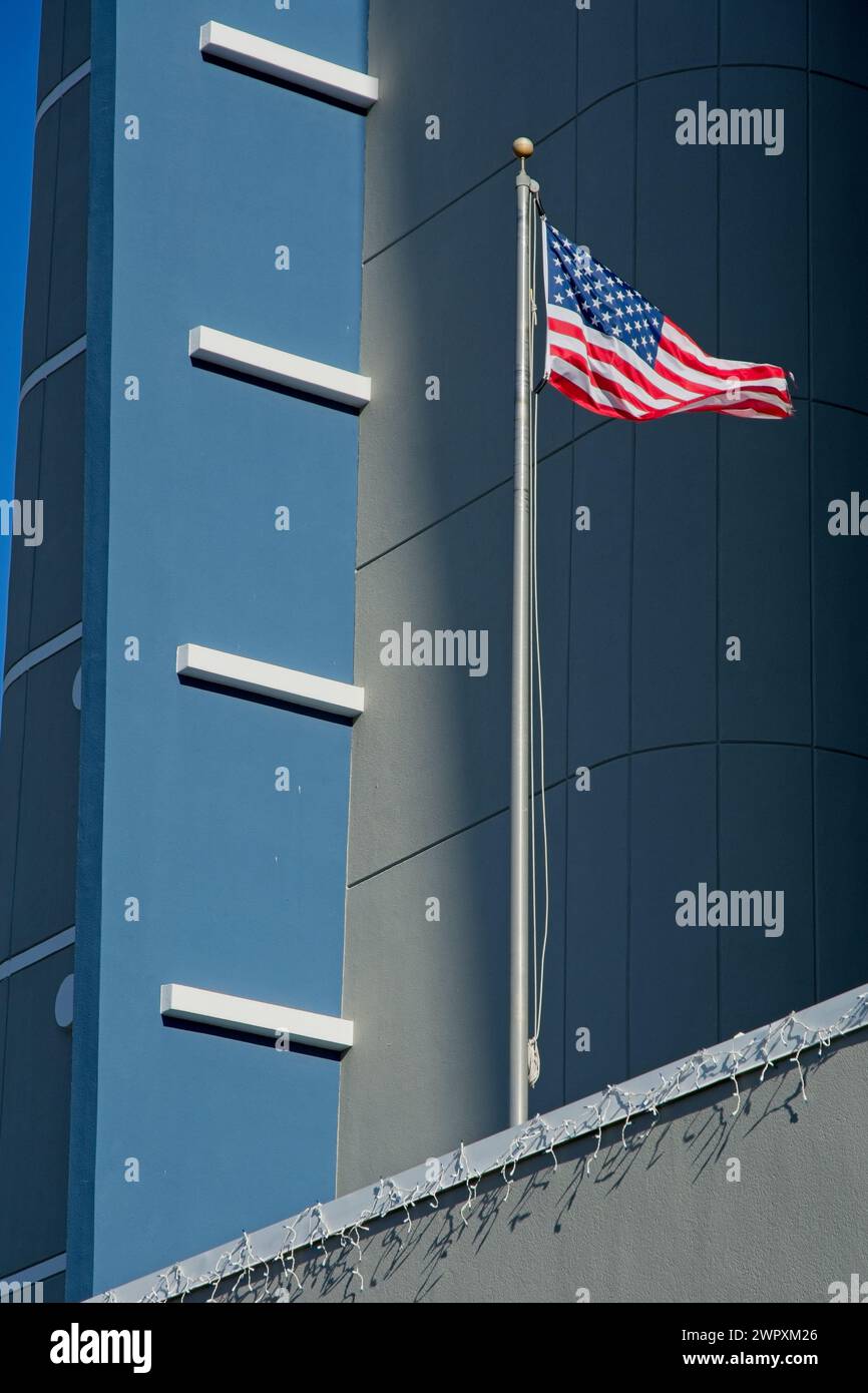 Sunlit American flag on pole standing before high-rise building Stock ...