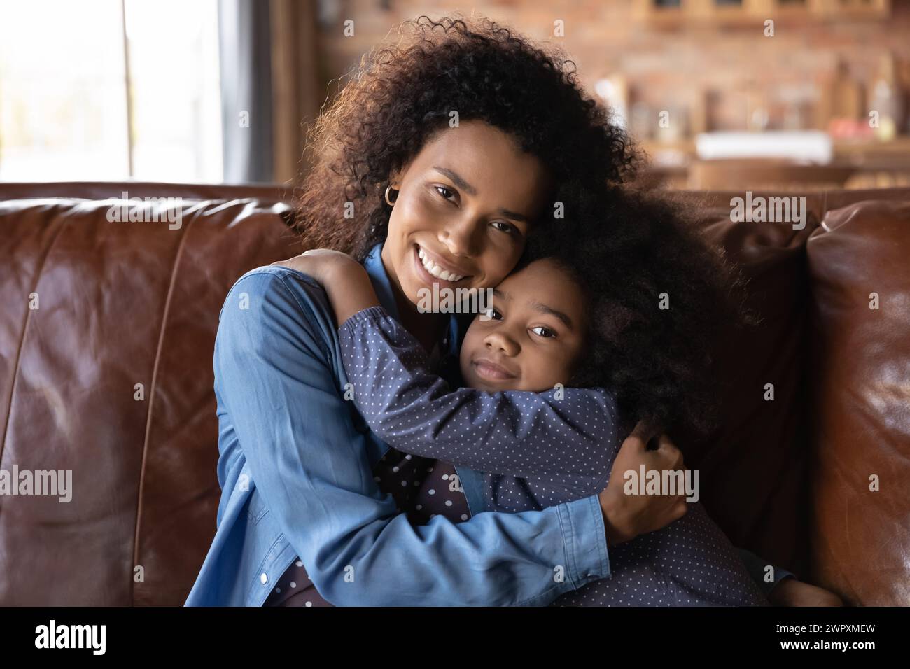 African woman hugging little daughter smile look at camera Stock Photo - Alamy