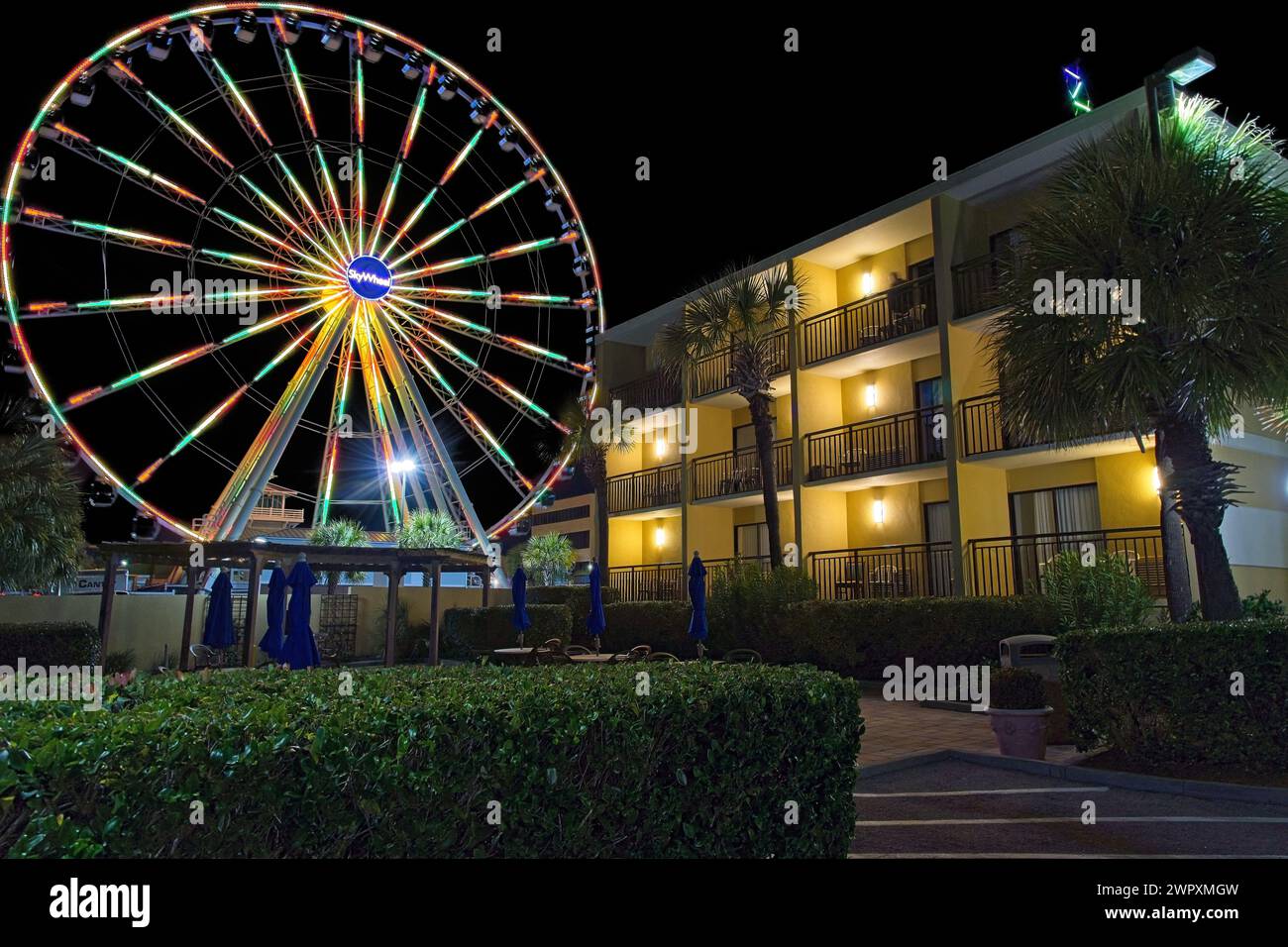 Illuminated ferris wheel behind hotel at night on boardwalk in Myrtle ...