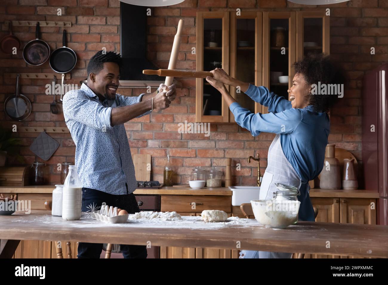 African couple have fun in kitchen holding rolling pins fighting Stock ...